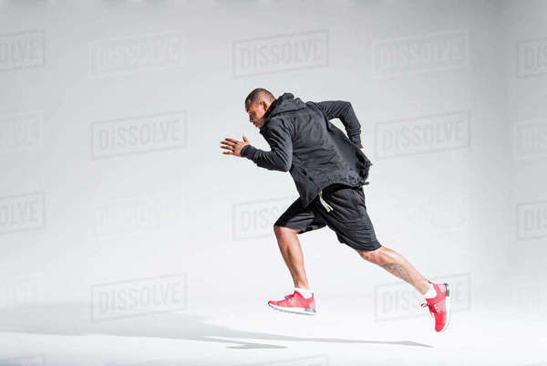Side view of young african american sportsman running on grey - Stock ...