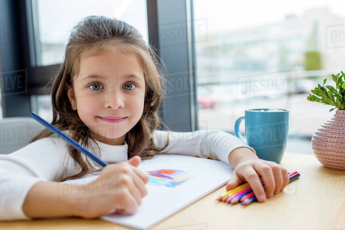 Adorable kid holding colored pencil and looking at camera - Stock Photo - Dissolve