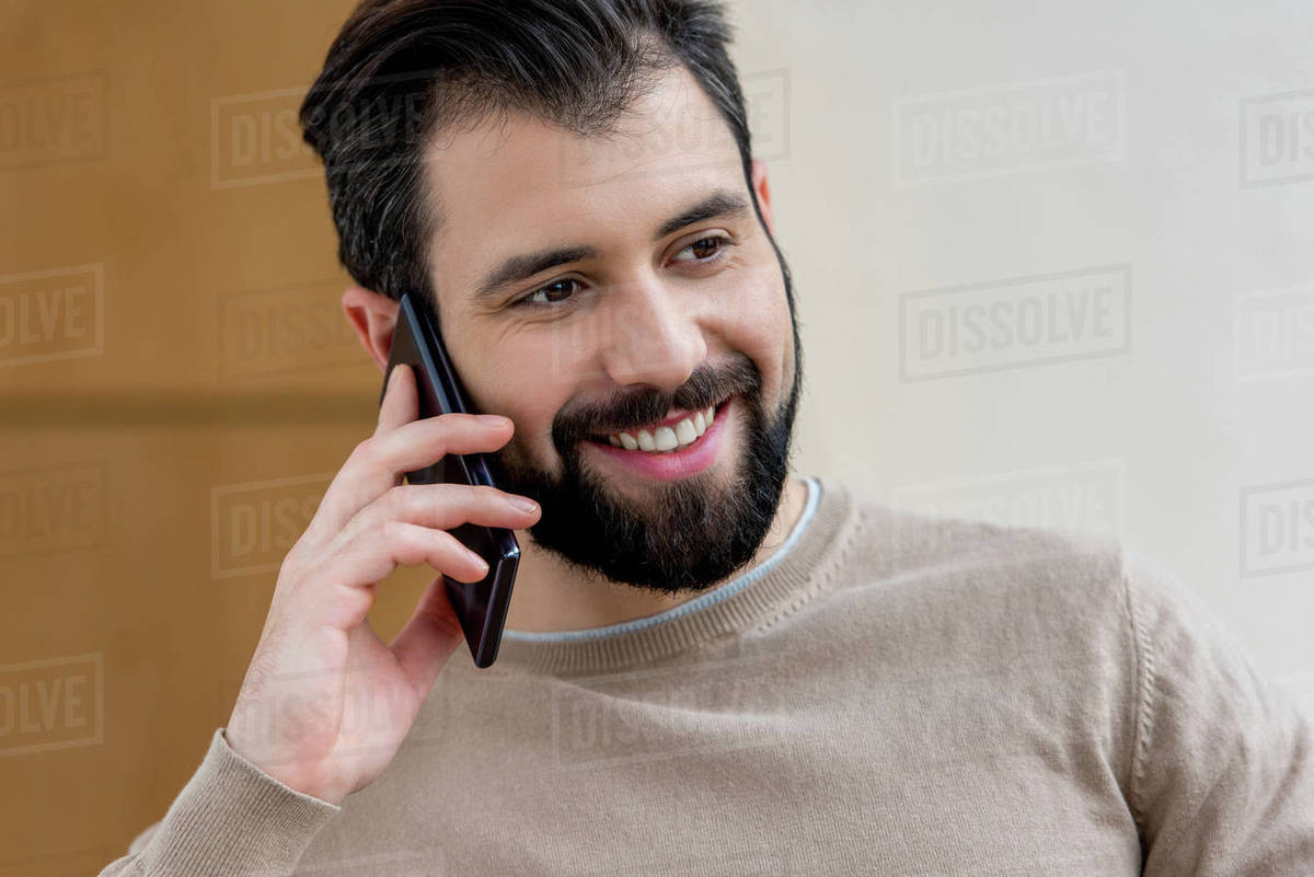 Smiling handsome man talking by smartphone - Stock Photo - Dissolve
