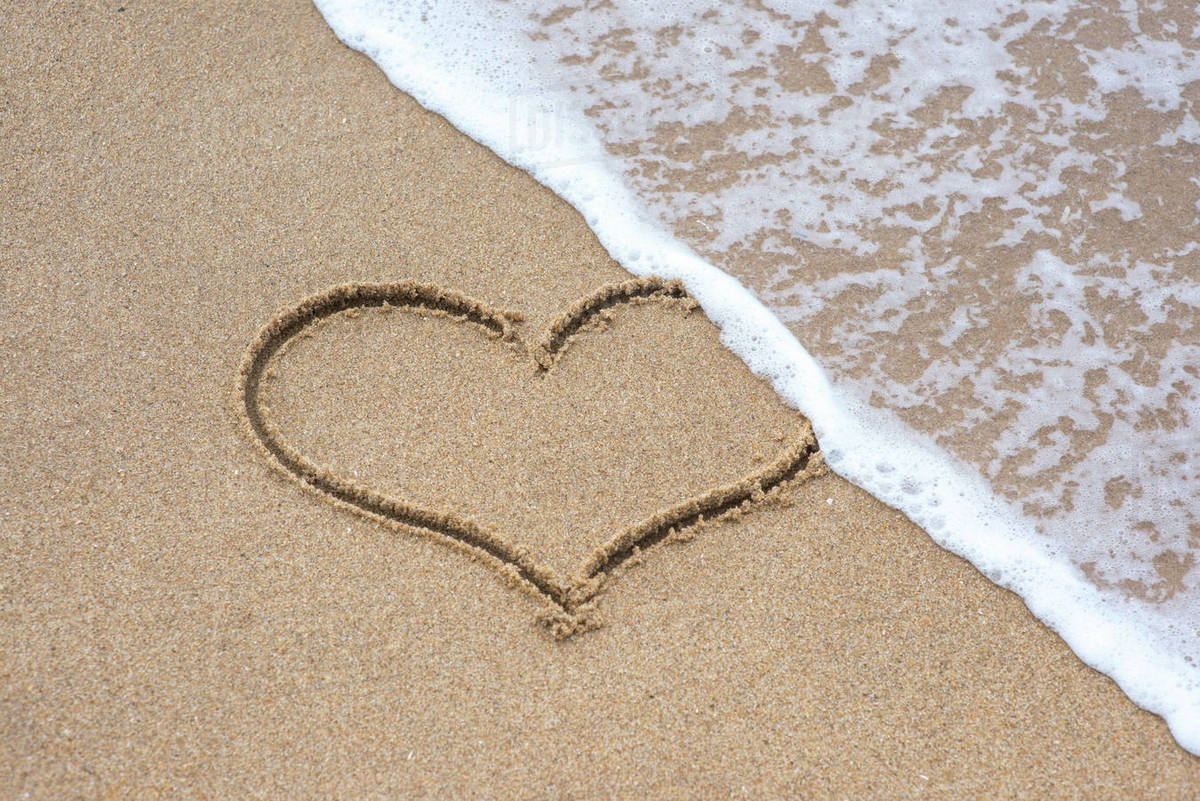 Heart shape sign erasing by sea wave on sandy beach - Royalty-free ...