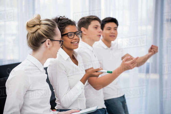 Young multicultural students looking and pointing on something ...