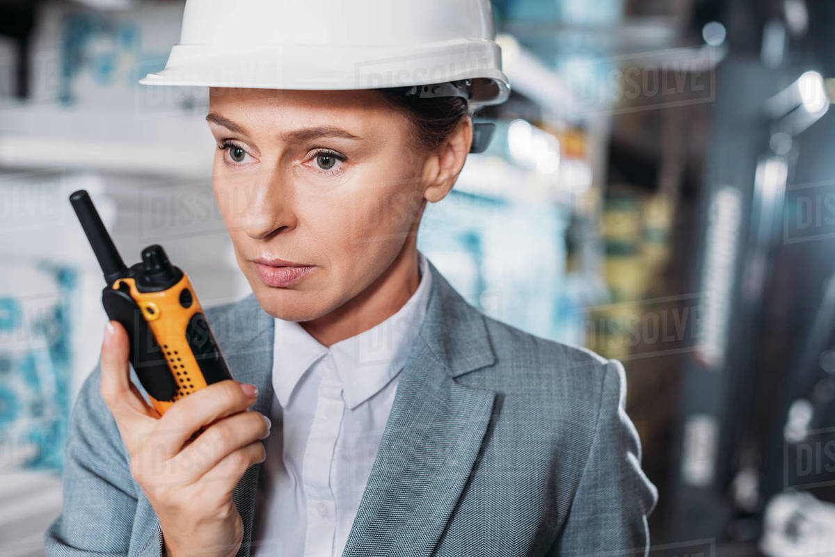 Female inspector in helmet with walkie talkie in warehouse - Stock ...