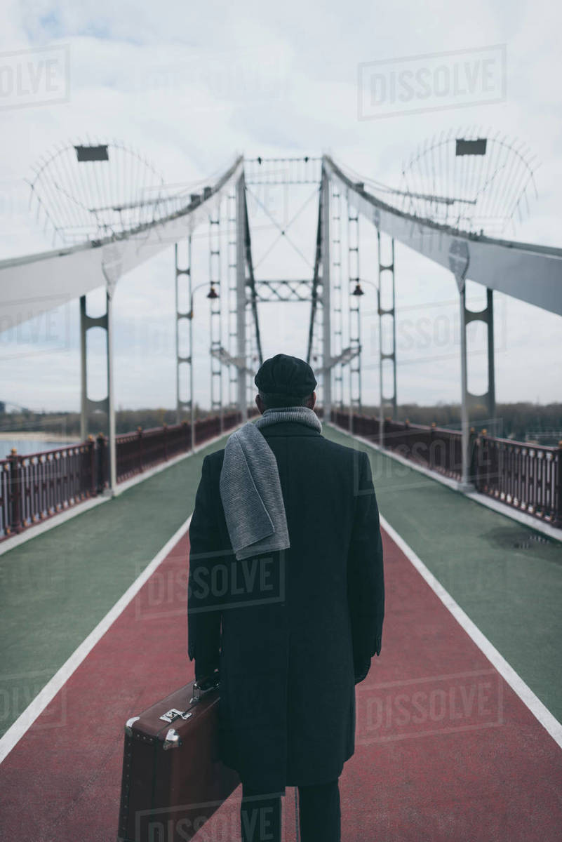 Back view of man with suitcase standing on pedestrian bridge - Royalty ...