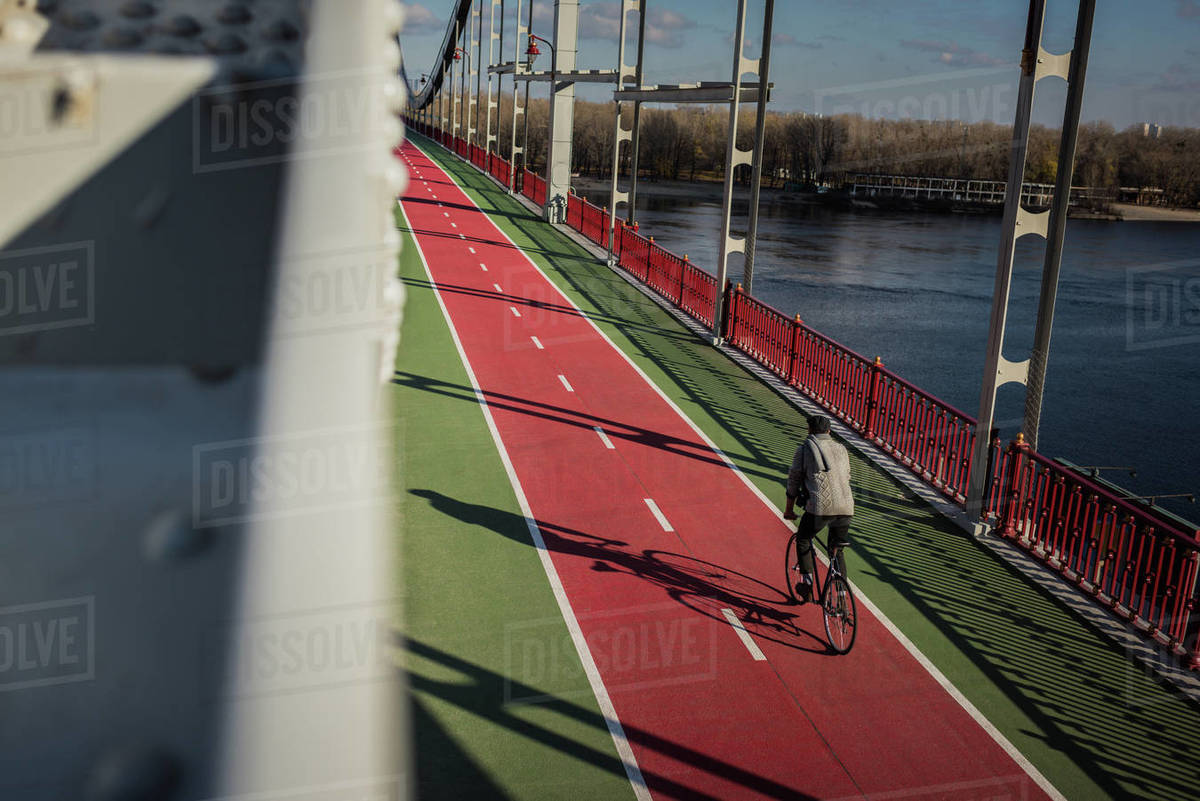 High angle view of man riding bicycle on pedestrian bridge over river ...