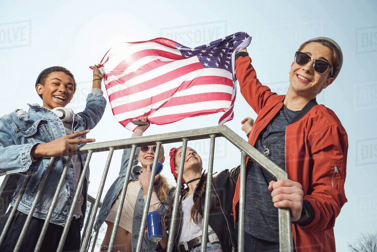 Teenagers having fun and waving american flag in skateboard park ...
