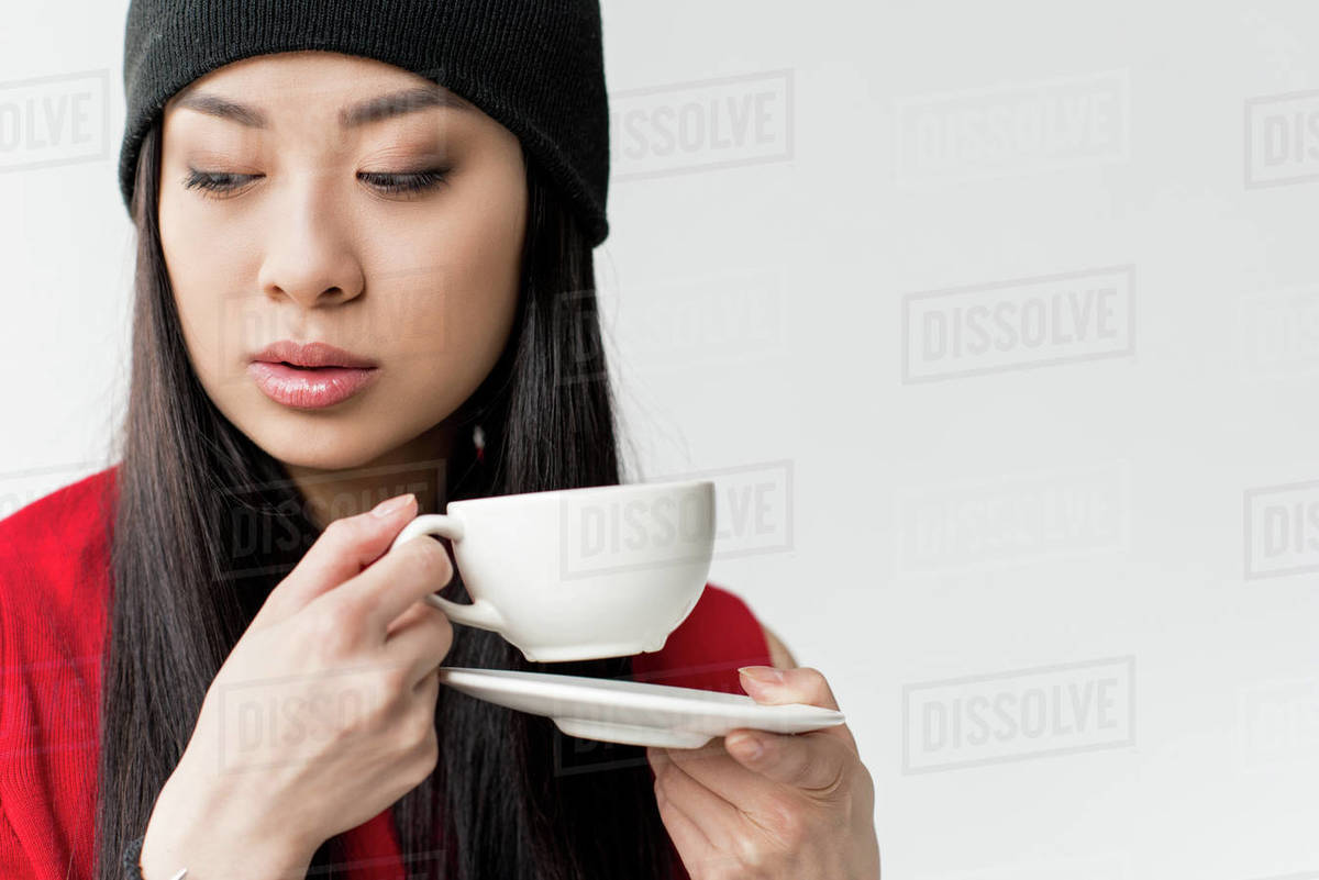 Portrait of attractive asian woman holding tea cup isolated on grey ...