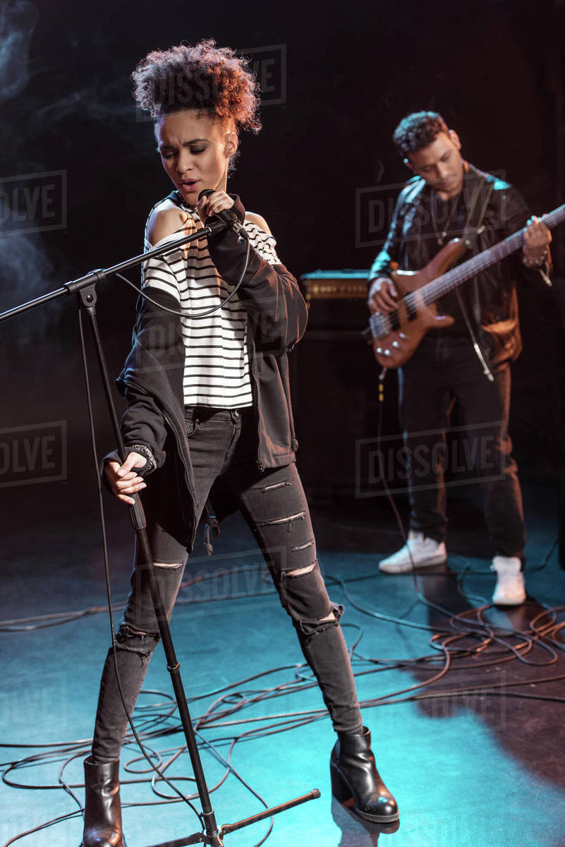 Female singer with microphone and rock and roll band performing hard ...
