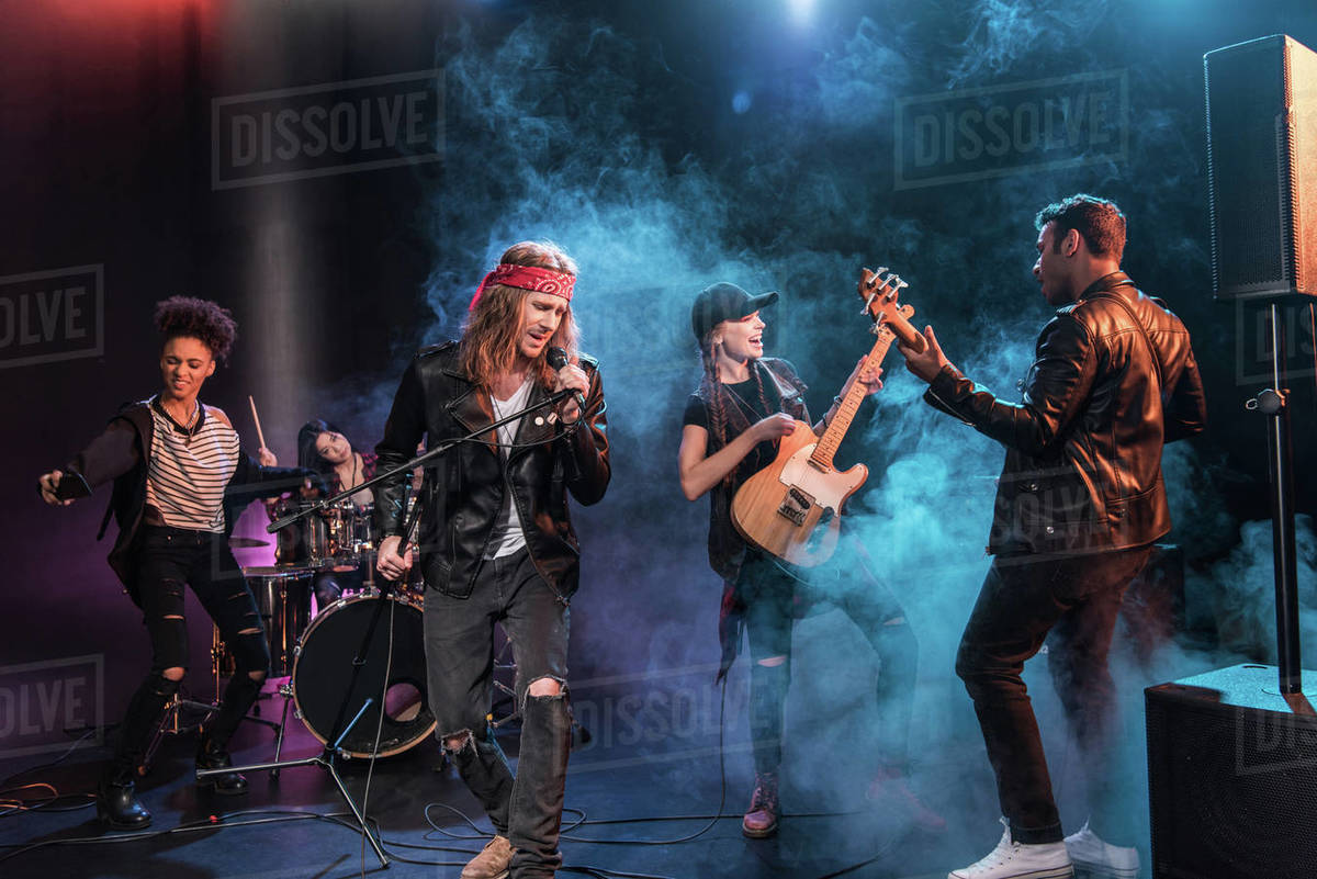 Handsome singer with rock and roll band performing music on stage ...