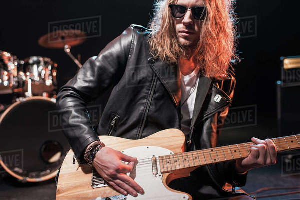 Handsome rock star in eyeglasses playing hard rock music with bass ...