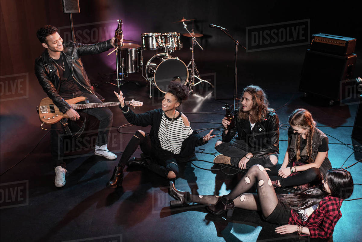 Young rock and roll band sitting together and drinking beer after ...