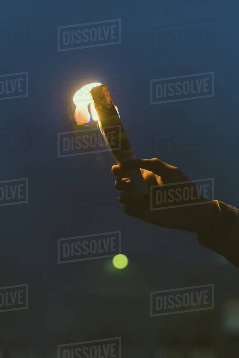 Cropped view of male hand with smoke bomb with fire at night - Royalty ...