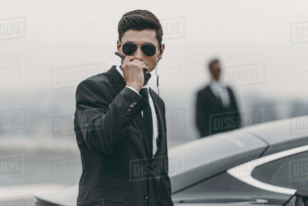 Handsome bodyguard in sunglasses talking by portable radio - Stock ...