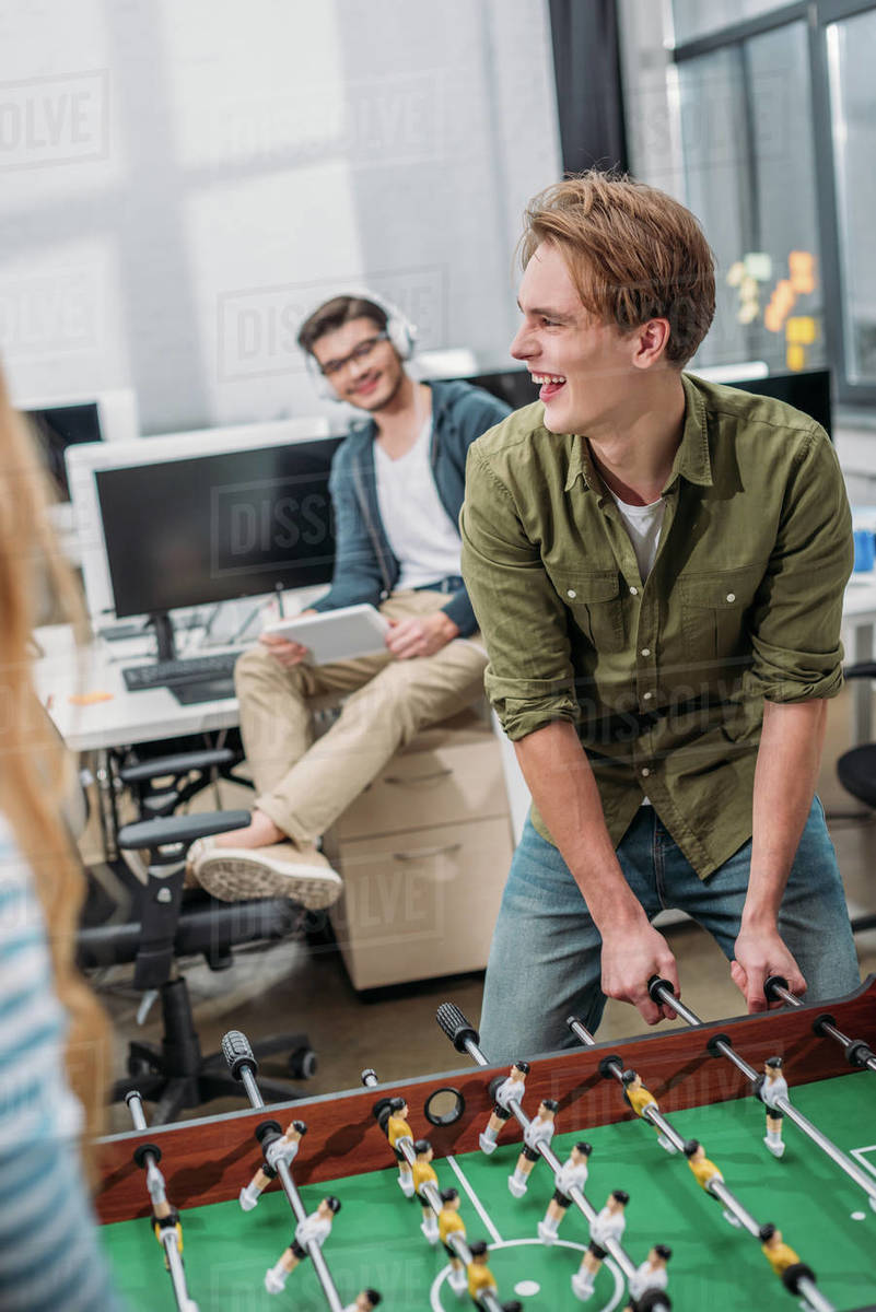 Cheerful office workers playing in table soccer at modern office ...