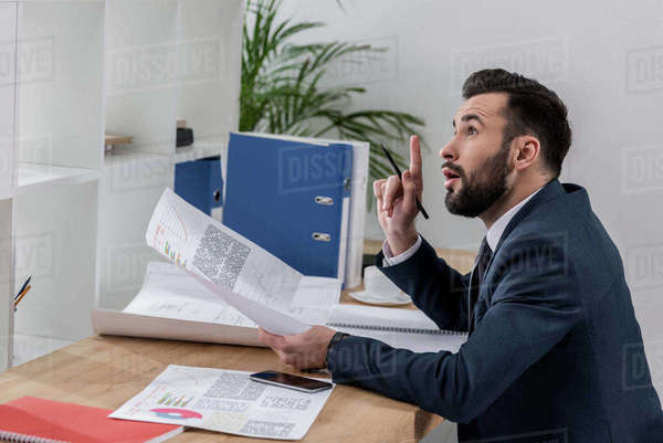 Businessman sitting at table and showing idea gesture - Royalty-free ...