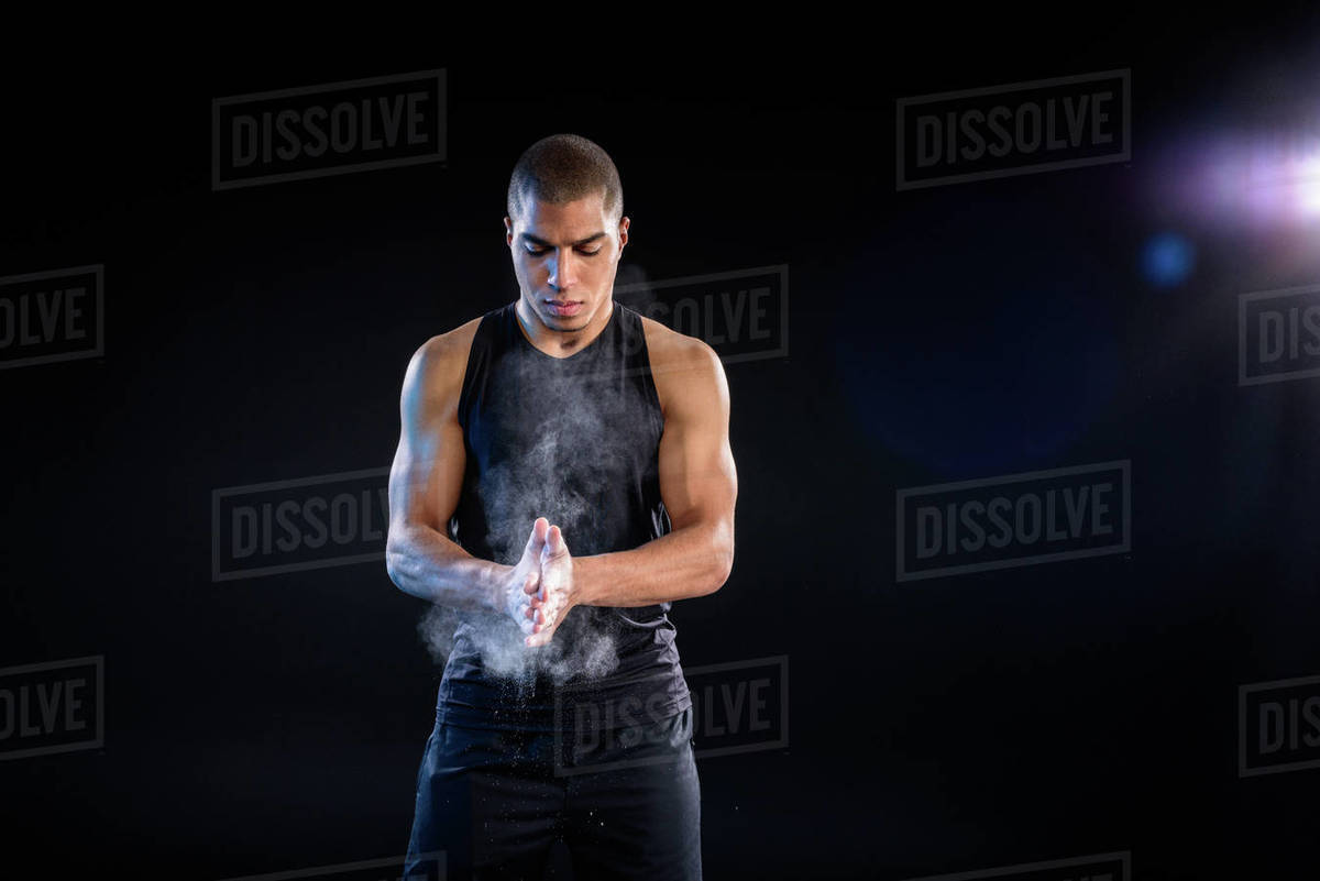 handsome african american sportsman clapping hands with talc on black ...