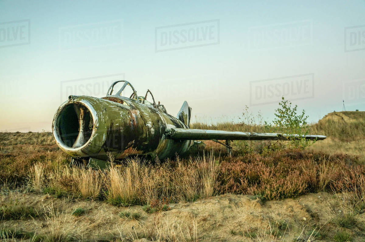 old rusty airplane lying in field - Stock Photo - Dissolve