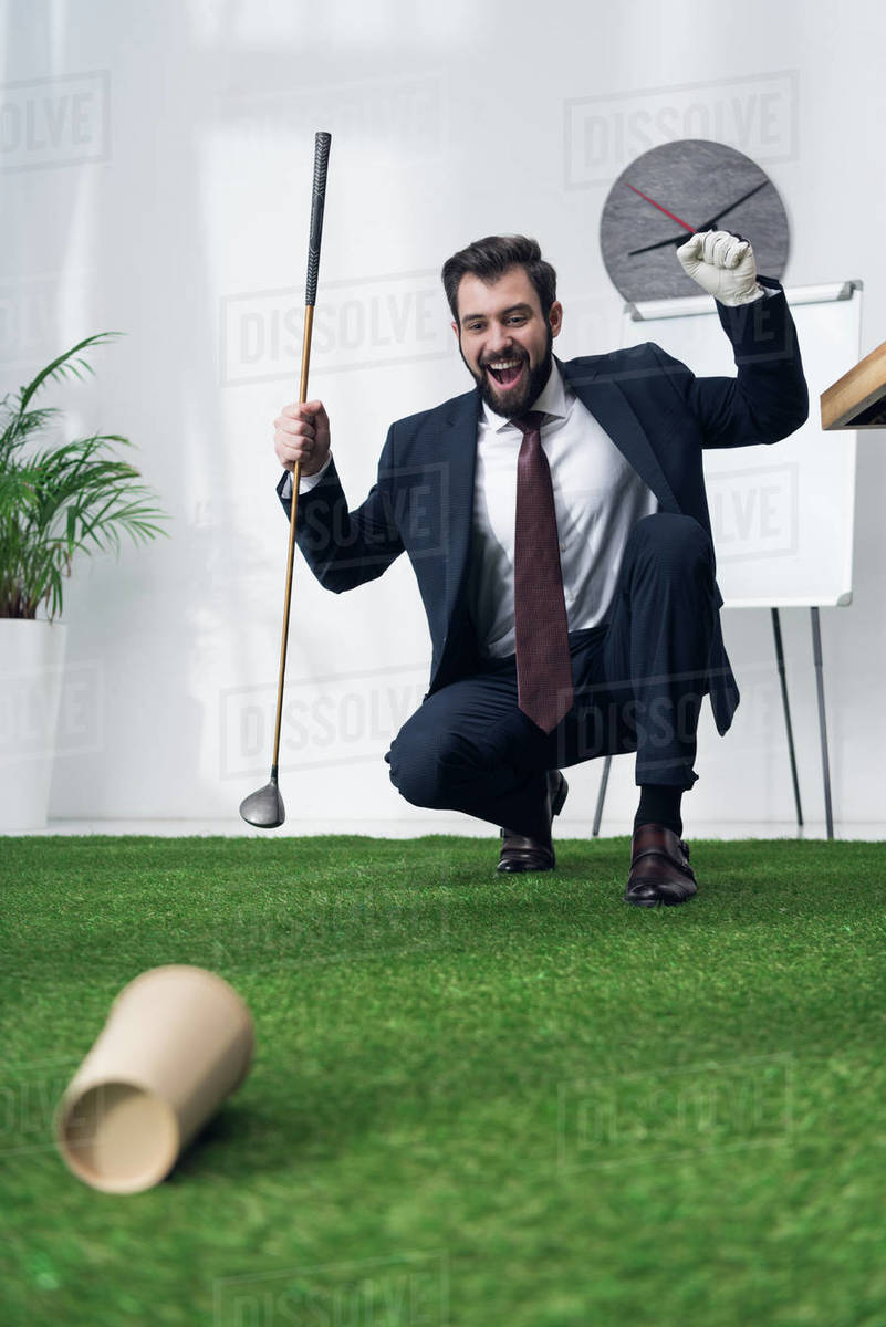 Excited young businessman playing golf in office - Royalty-free Stock ...