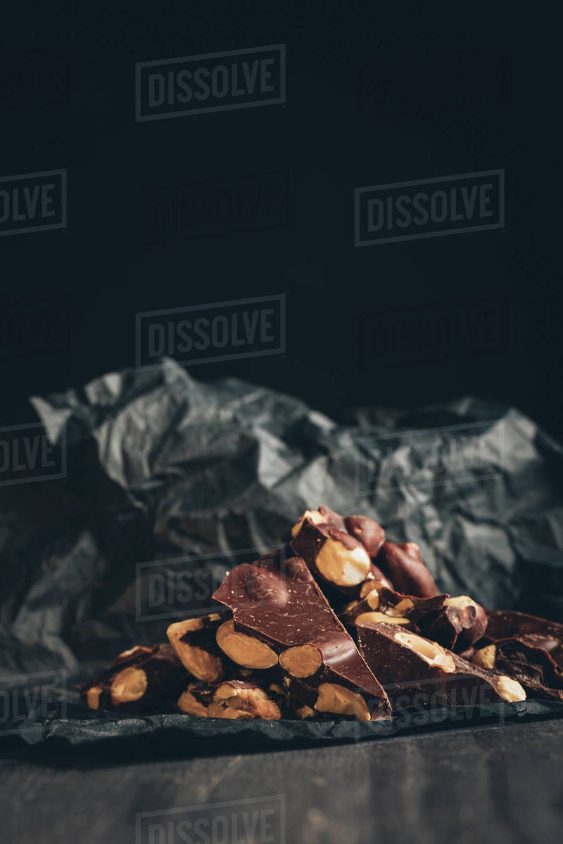 Appetizing chocolate with nuts pieces on dark gray crumpled paper ...