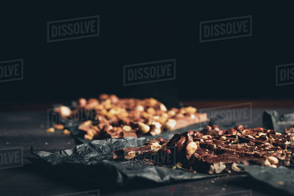 Dark and milk chocolate with nuts on a gray wrapper on a table ...