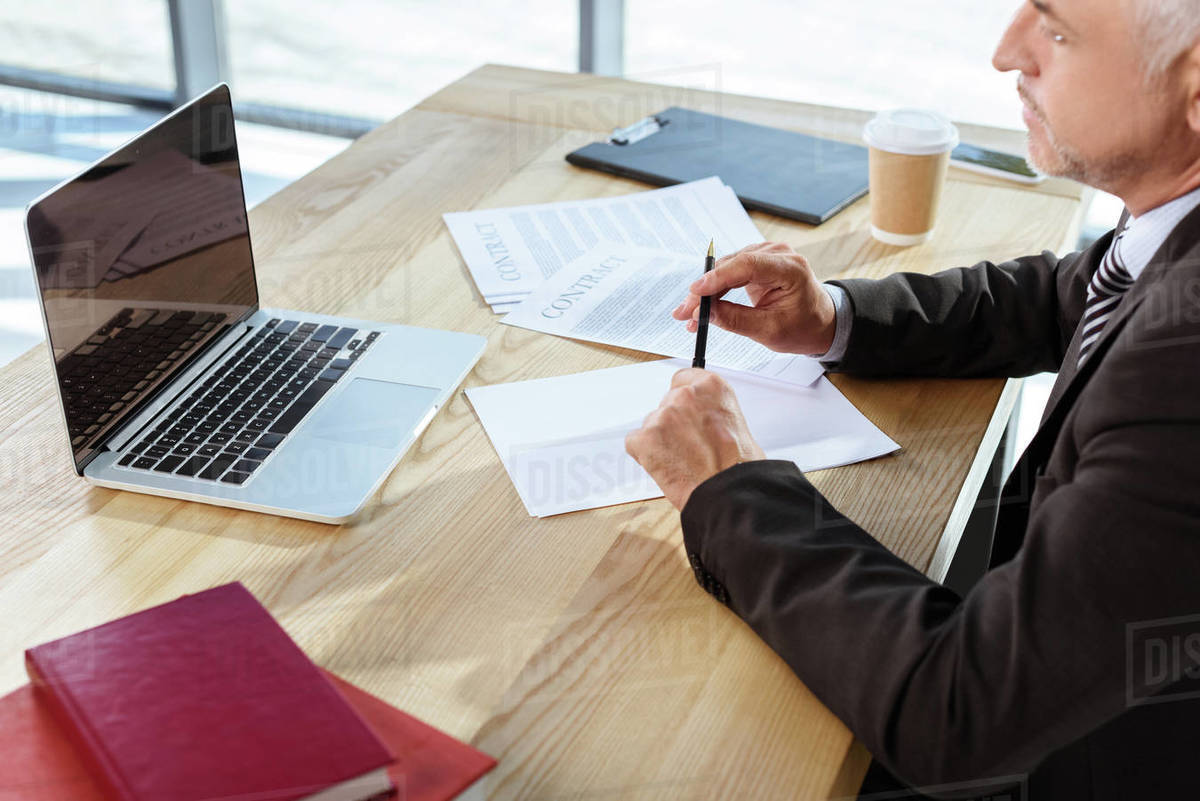 Mature serious businessman looking at laptop - Stock Photo - Dissolve