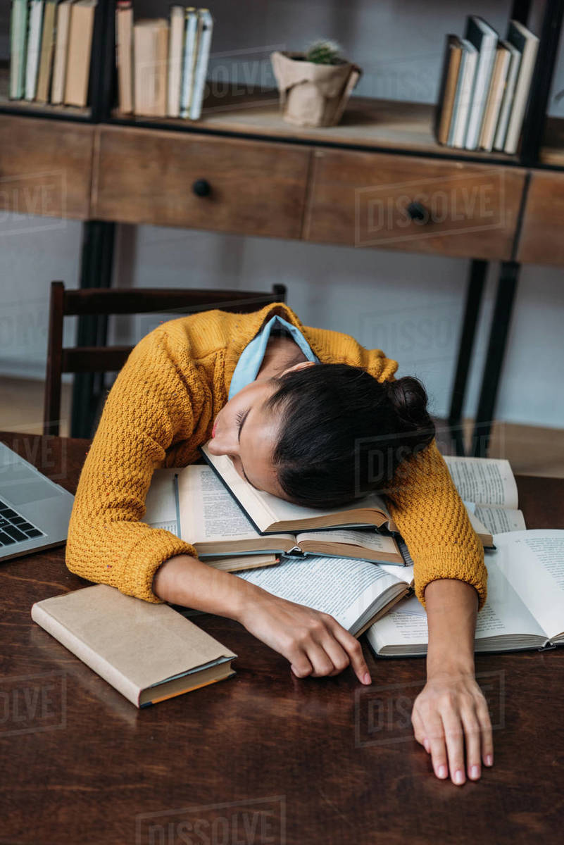 overworked student girl sleeping at library while preparing for exam at ...
