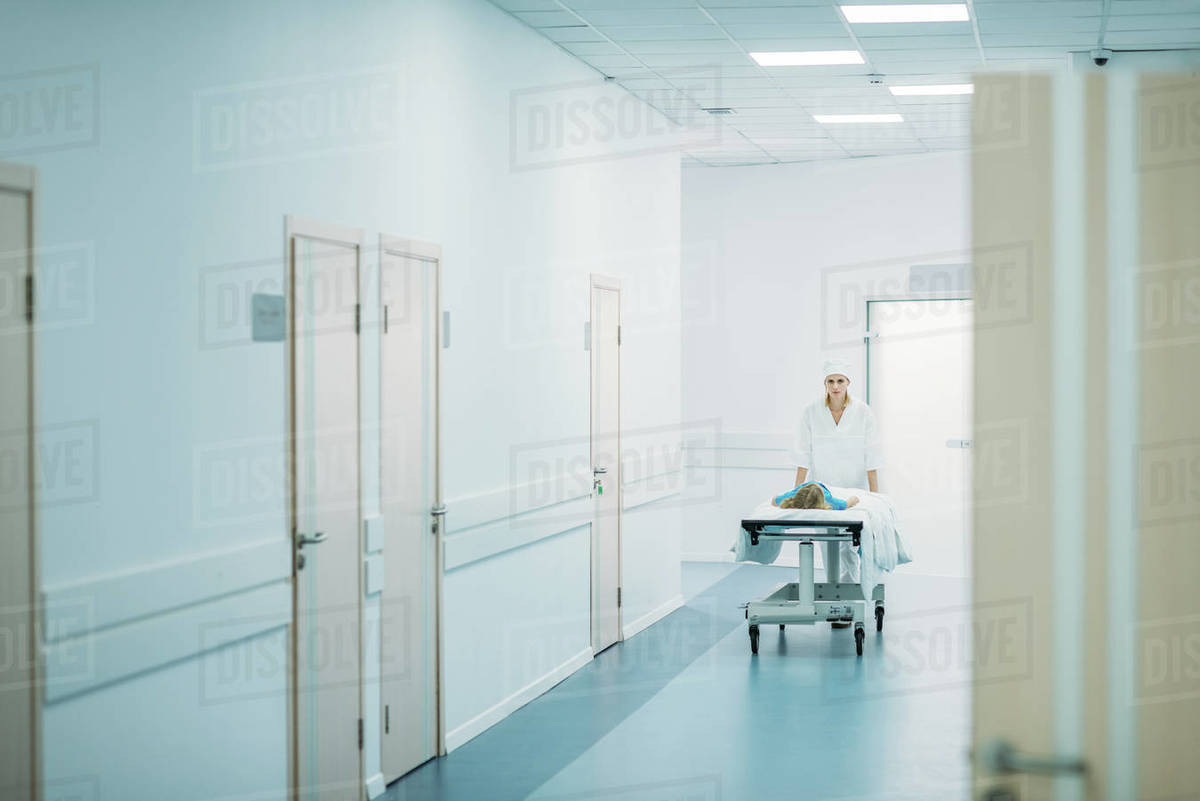 doctor moving preschooler patient on medical stretcher in corridor ...