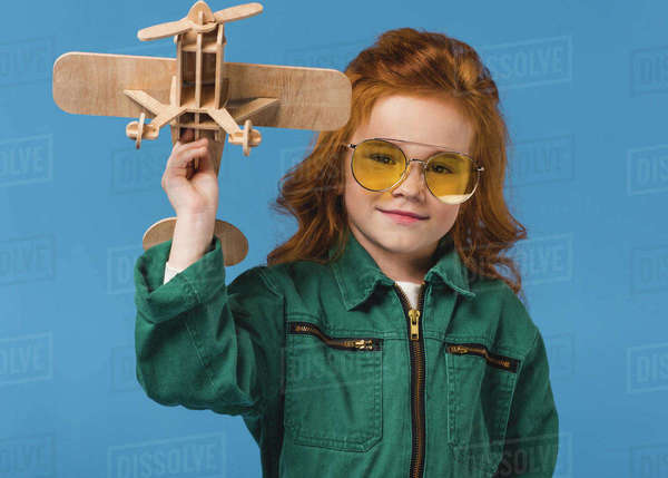 portrait of smiling child in pilot costume with wooden plane toy ...