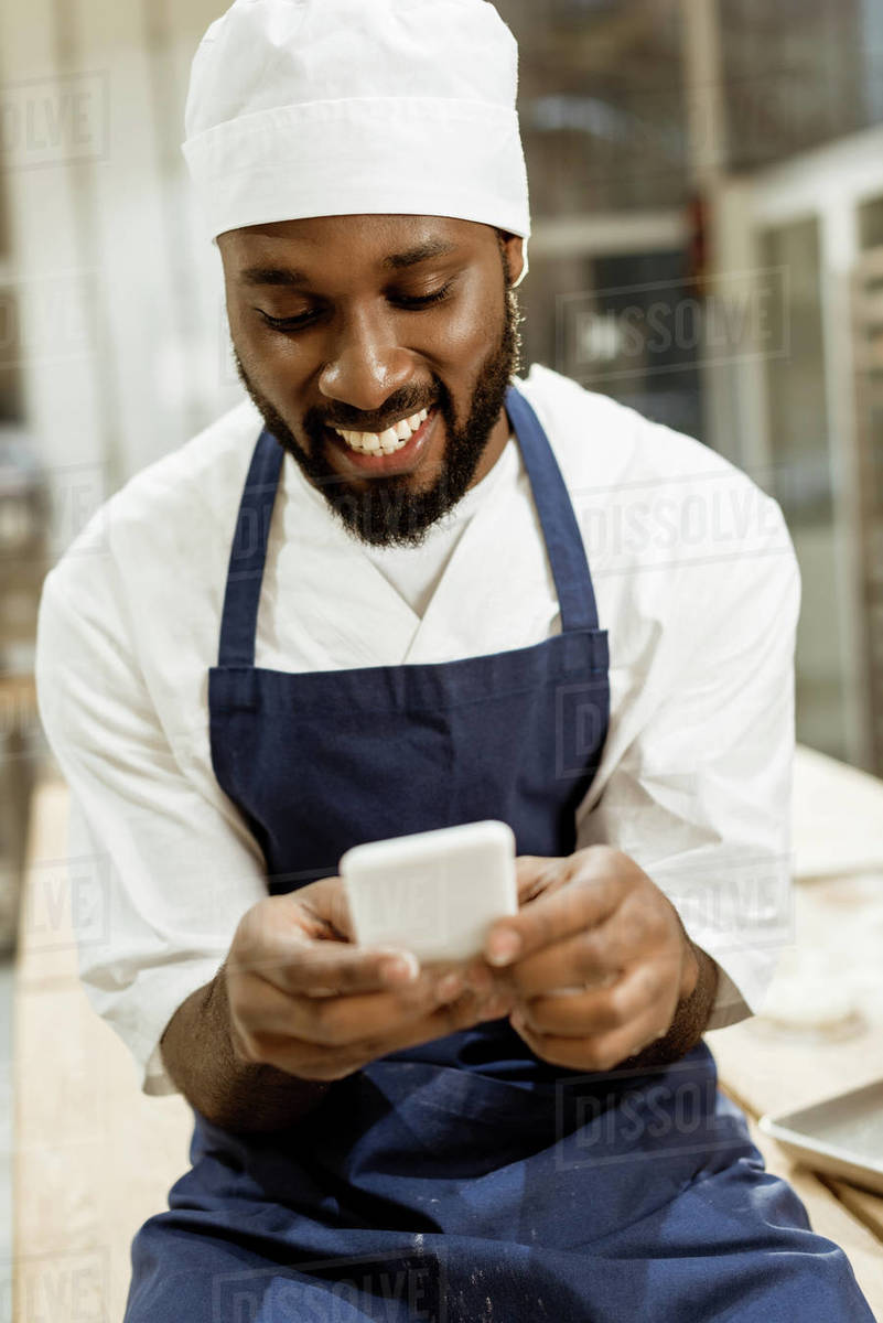 Young african american baker with hands covered in flour using ...