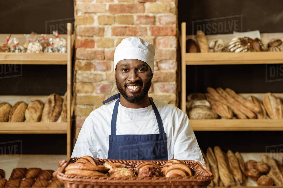 Smiling african american baker holding basket with sweet pastry - Stock ...