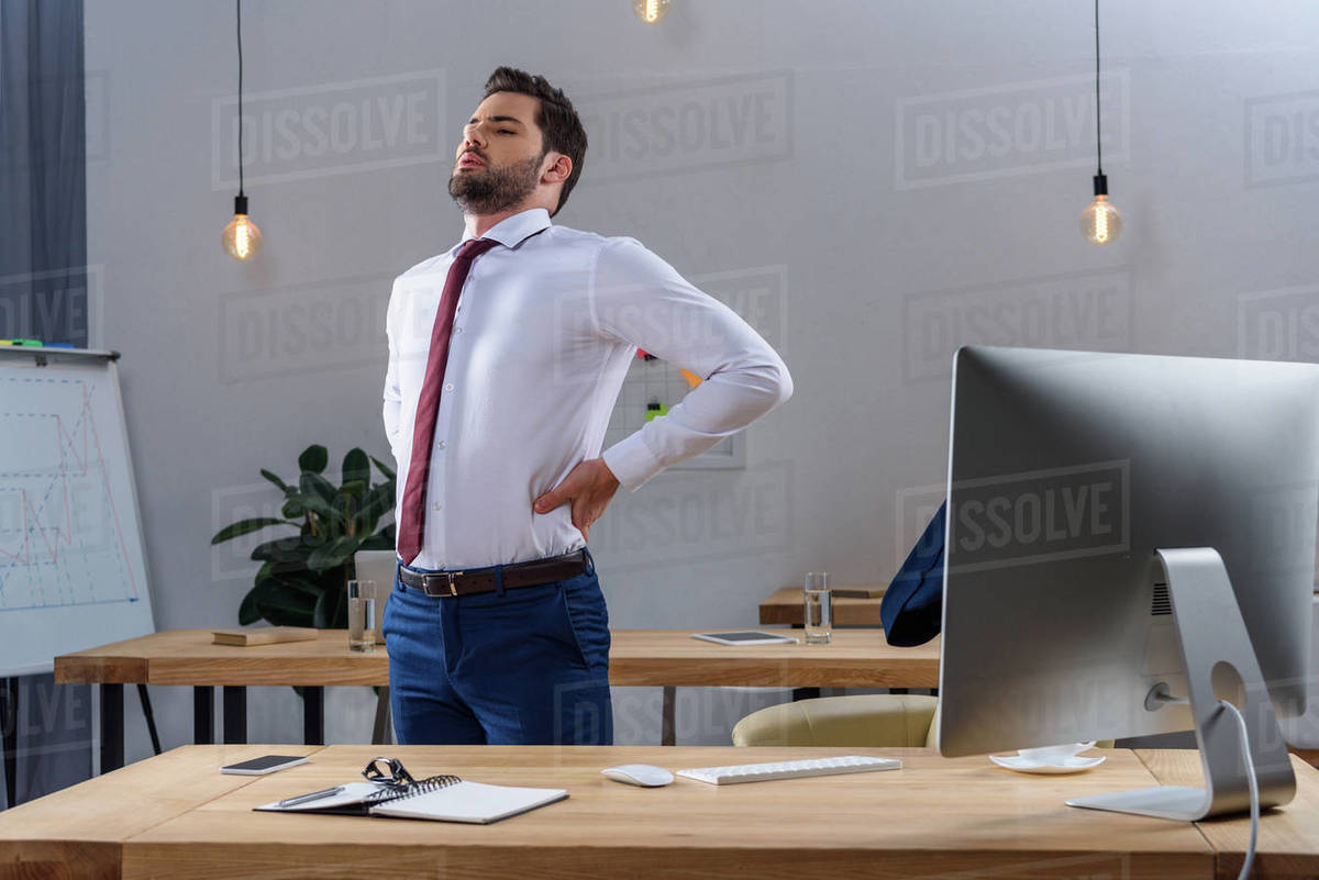 Tired businessman standing and stretching in office - Royalty-free ...