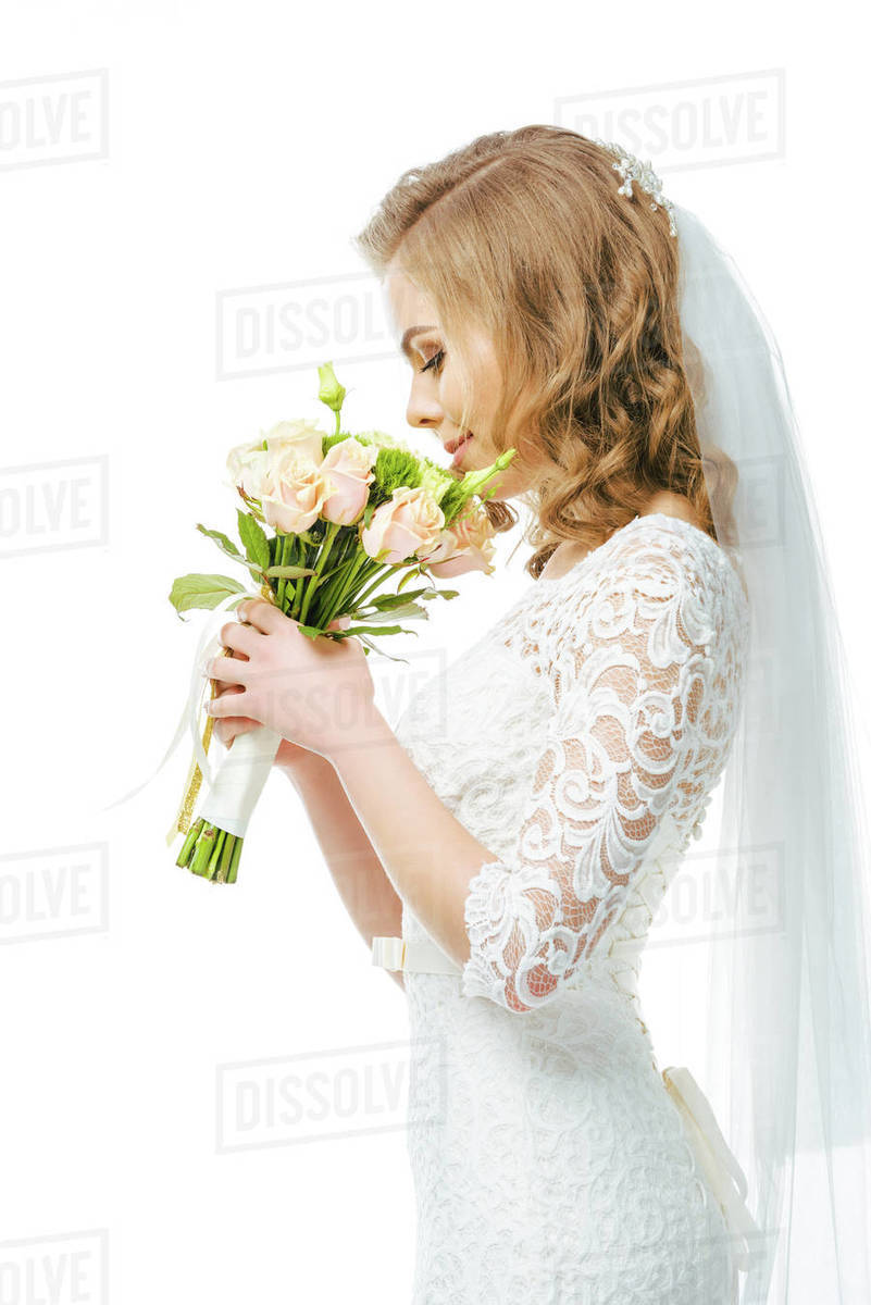 Side view of attractive bride in wedding dress and veil with bouquet of ...