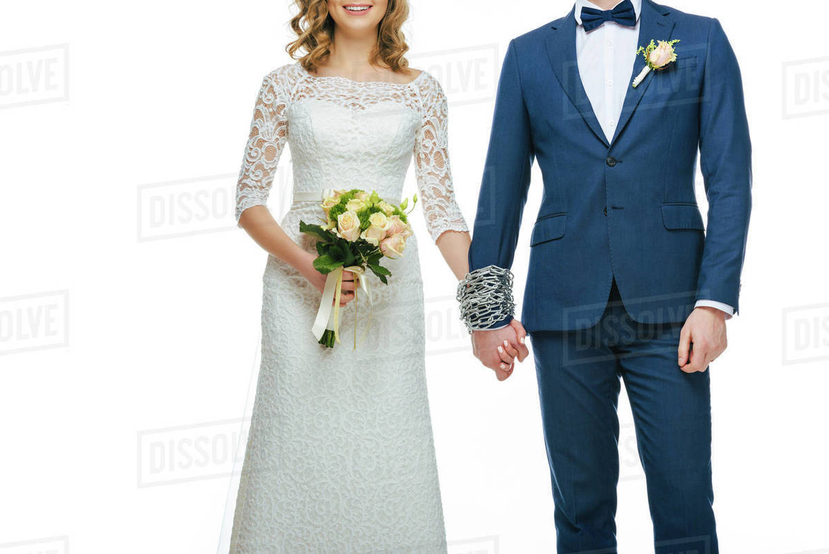 Cropped shot of chained wedding couple holding hands isolated on white ...