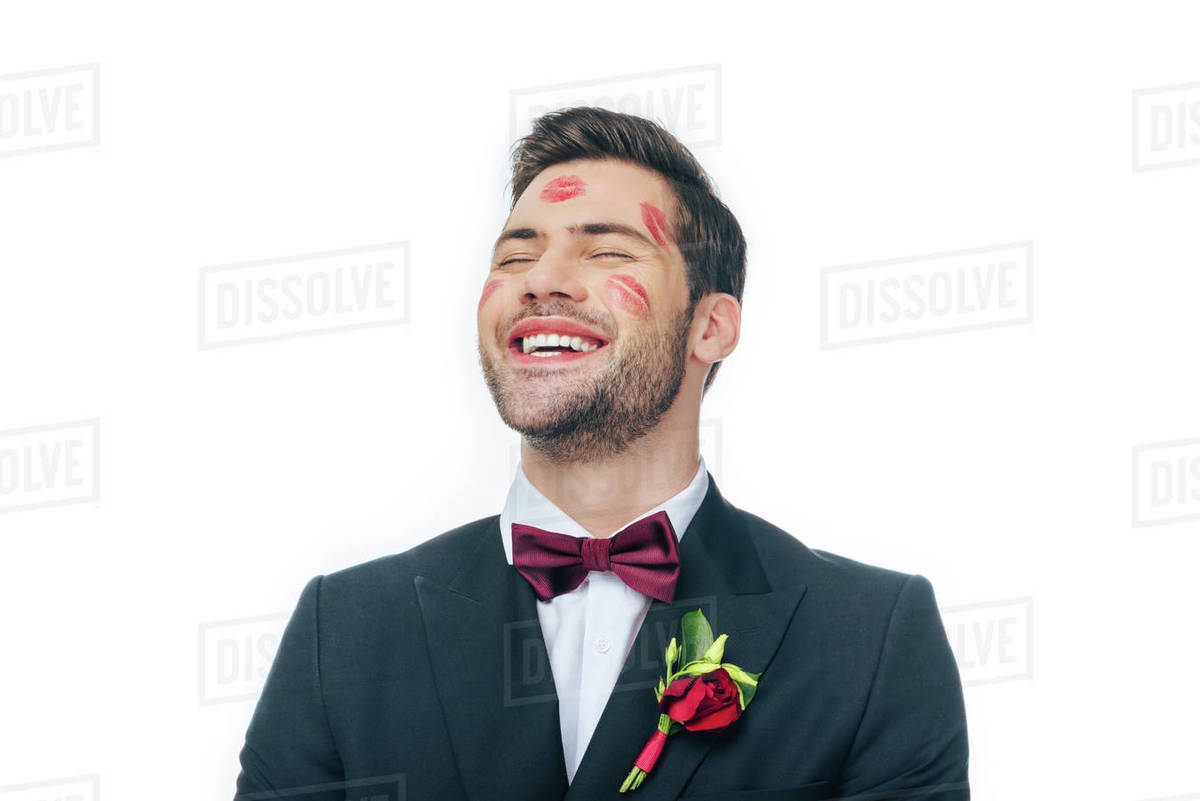 Portrait of handsome happy groom in suit with red lipstick on face ...