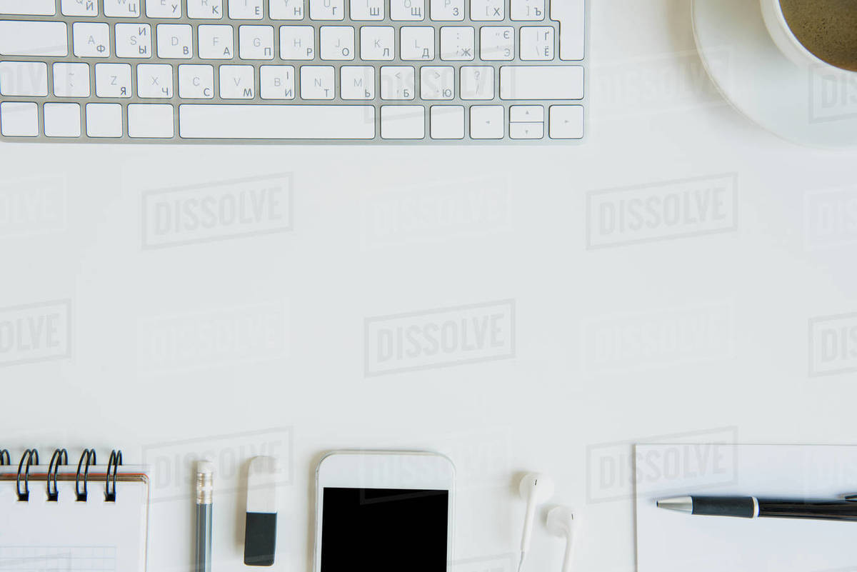 Top view of keyboard with office supplies and smartphone on table top ...
