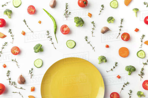 Top view of yellow plate on table with cut vegetables isolated on white ...