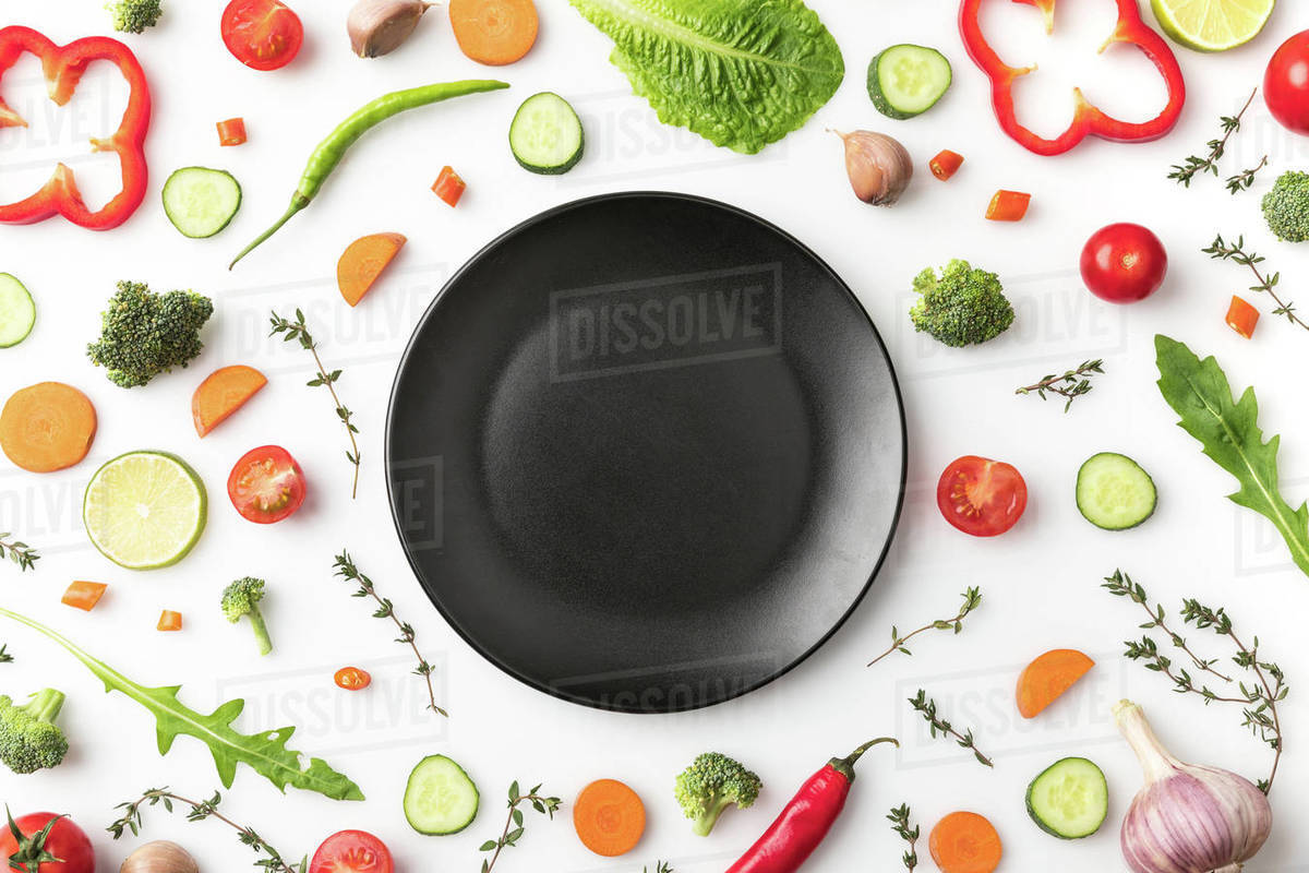 Top view of black plate in circle of cut vegetables isolated on white ...