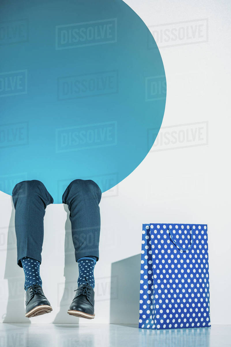 Cropped shot of young man with shopping bag falling into hole on grey ...