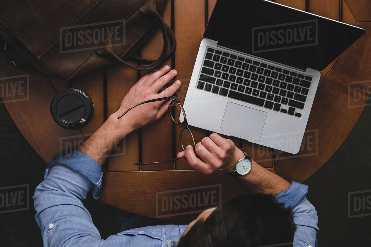 Overhead view of man using laptop with website while sitting at table ...