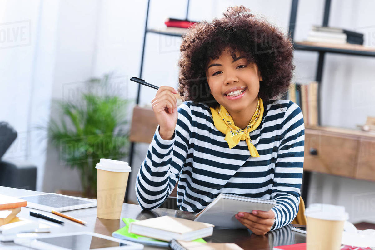Portrait of smiling African American student with notebook studying ...