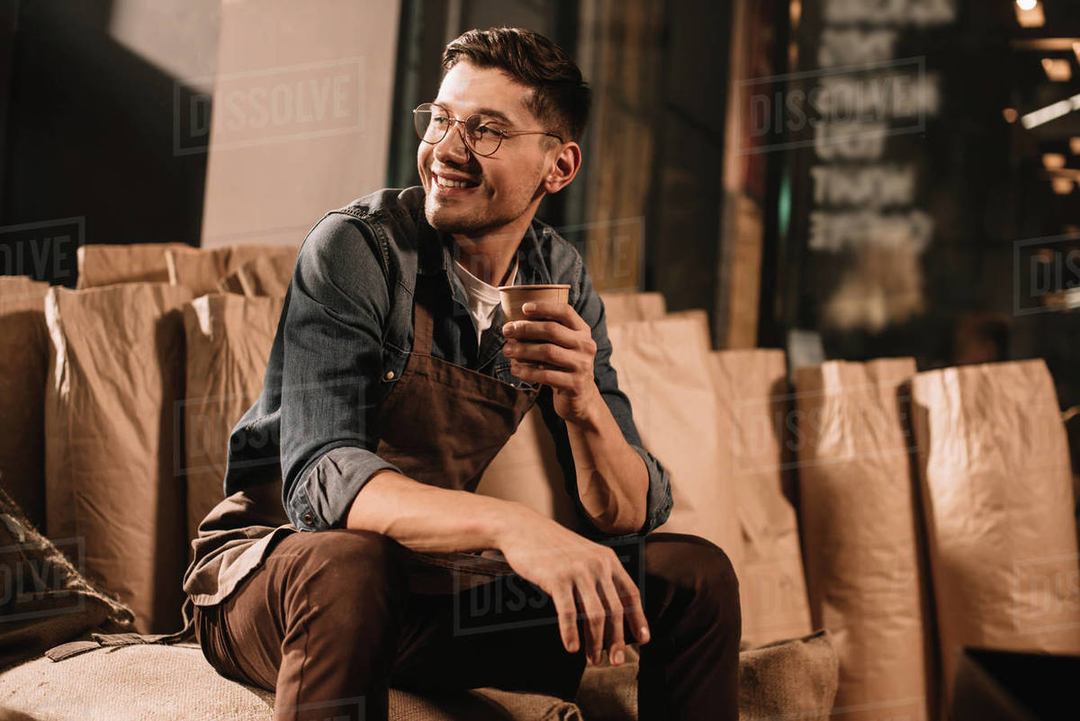 Smiling coffee roster with cup of coffee having break during work ...