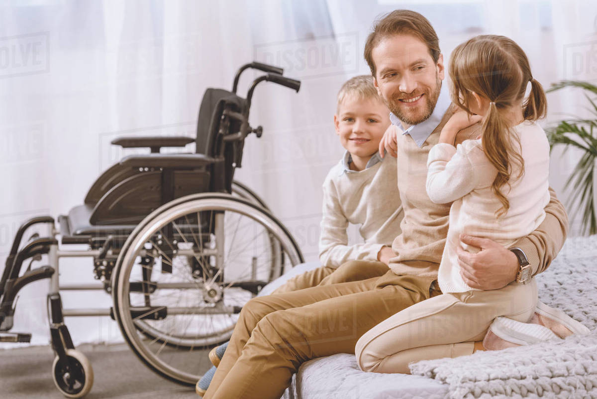 happy father with disability sitting with children on bed - Royalty ...