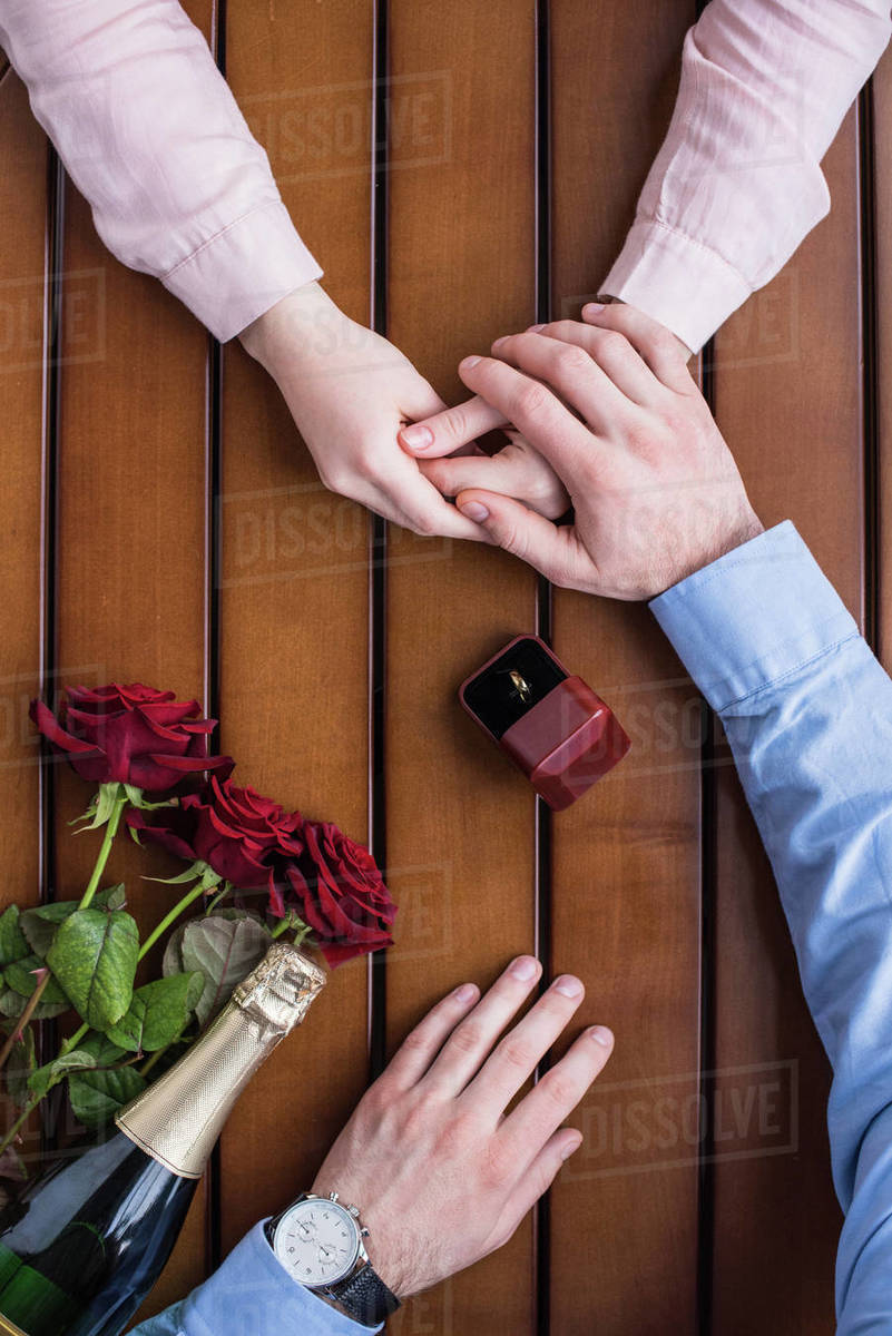 cropped image of boyfriend proposing girlfriend and holding her hand ...