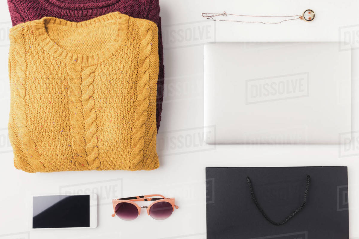 Flat lay with knitted sweaters, sunglasses, pendant, laptop, smartphone ...