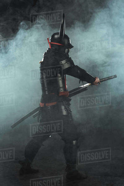 Side view of samurai taking out his katana on dark background with ...