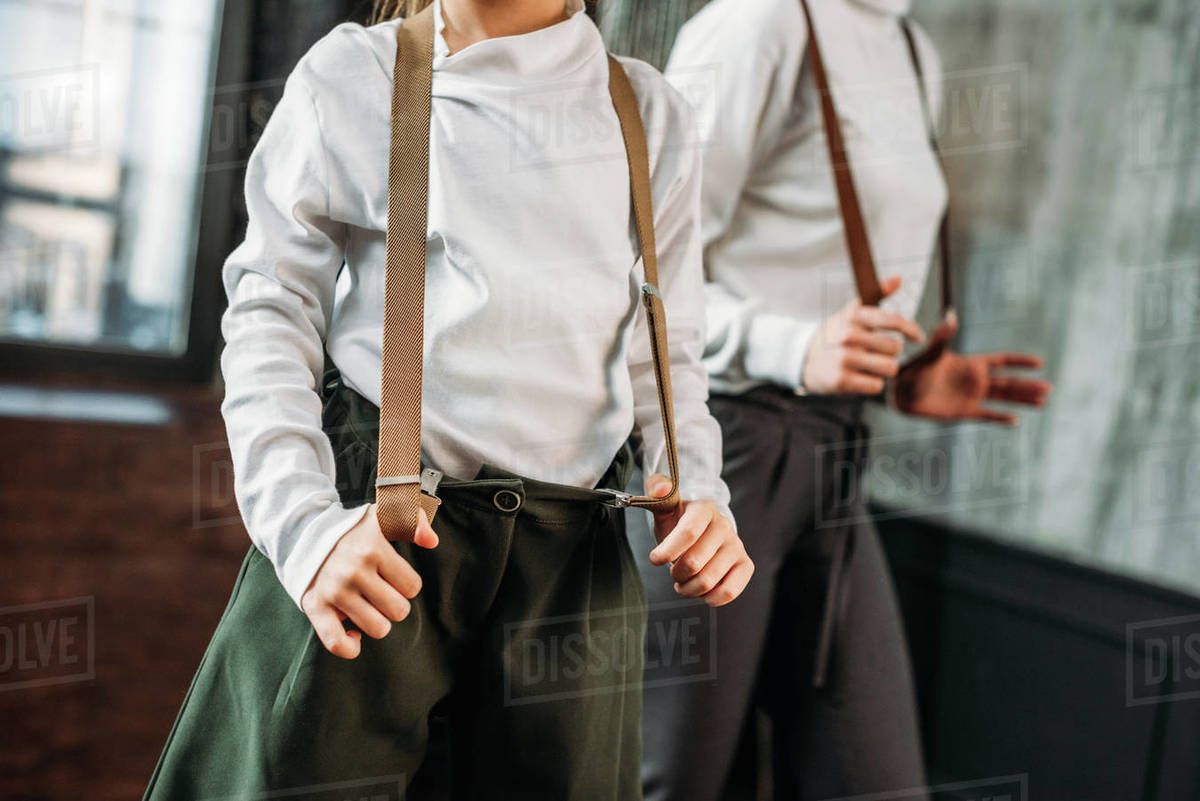 Cropped shot of mother and daughter in stylish clothing with suspenders ...