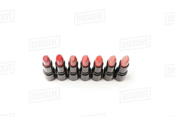 High angle view of row of different shaded lipsticks isolated on white ...