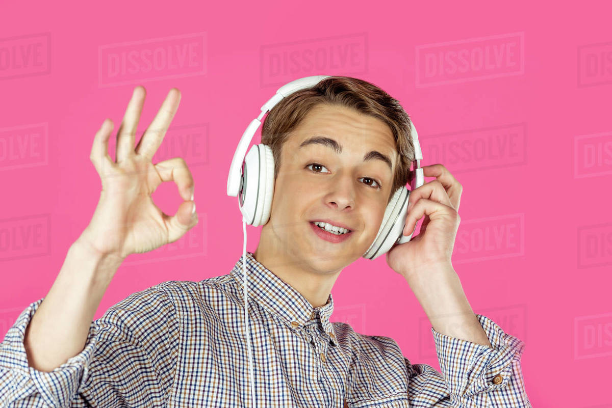 Teen boy in headphones showing okay sign isolated on pink - Royalty ...