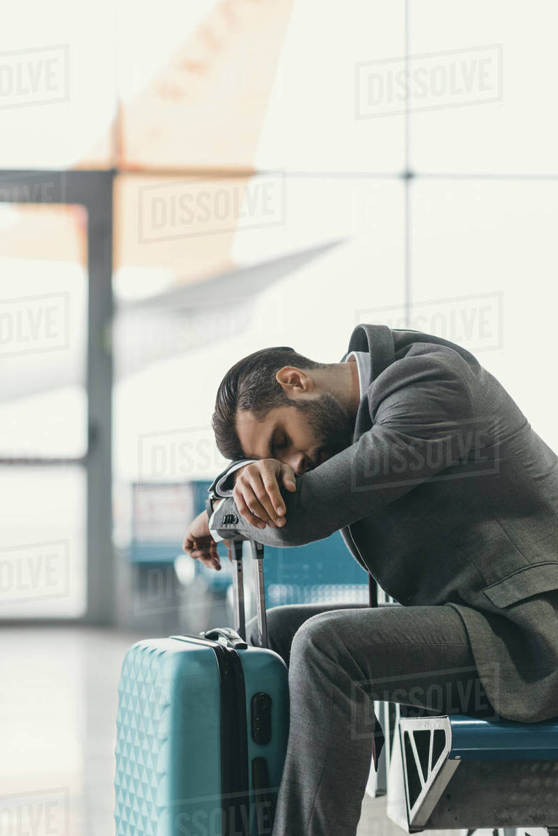 Exhausted businessman sleeping at airport lobby while waiting for ...
