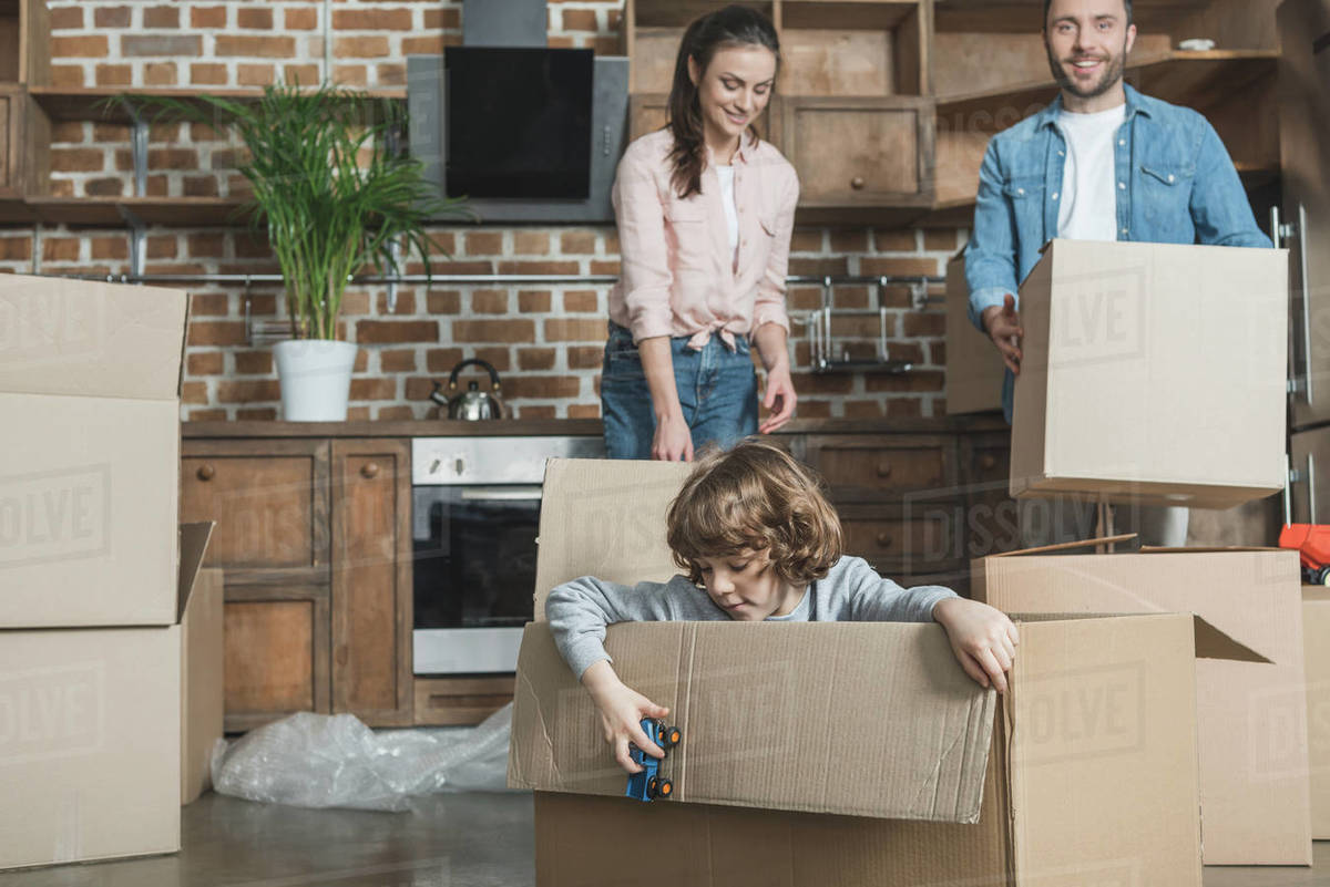 Happy family with one child packing boxes while moving home - Stock ...