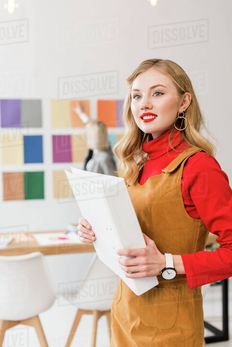 Attractive magazine editor with folder in modern office with colleague ...